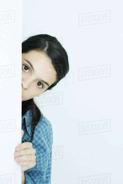 Teen girl peeking around wall, looking at camera - Royalty-free Stock ...