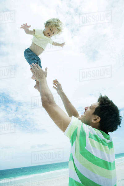 Man throwing child into air on beach - Stock Photo - Dissolve