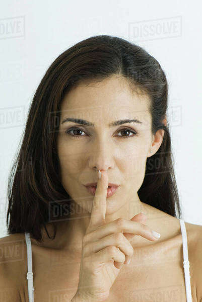 Woman holding finger over lips, looking at camera, portrait - Royalty ...