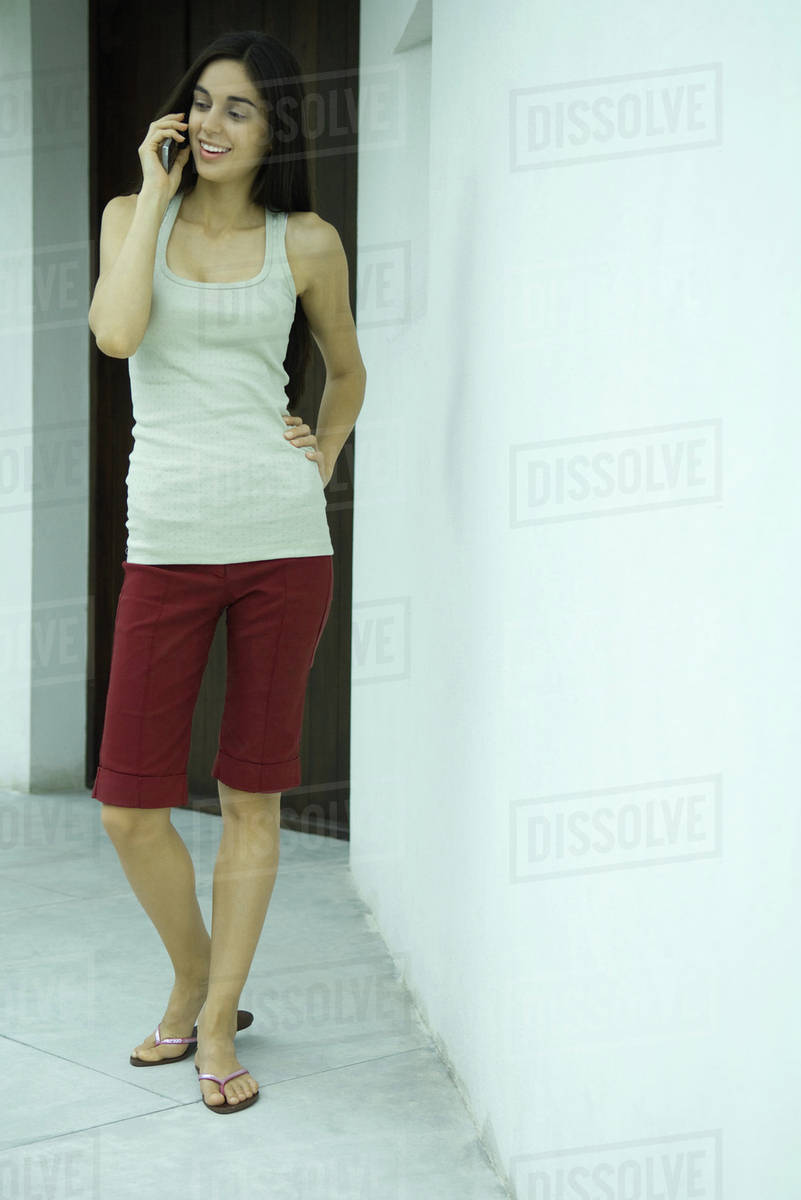 Woman standing using phone, full length portrait - Stock Photo - Dissolve