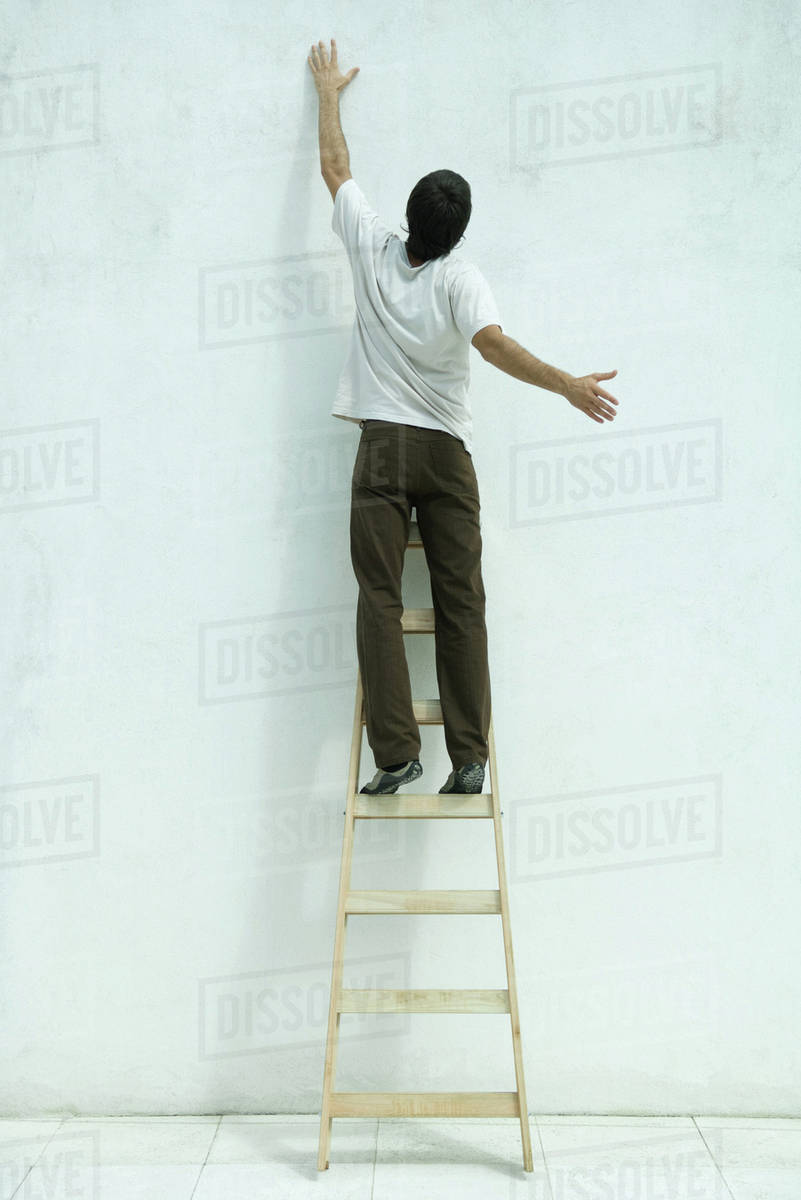 Man standing on ladder, arm raised, rear view - Royalty-free Stock ...