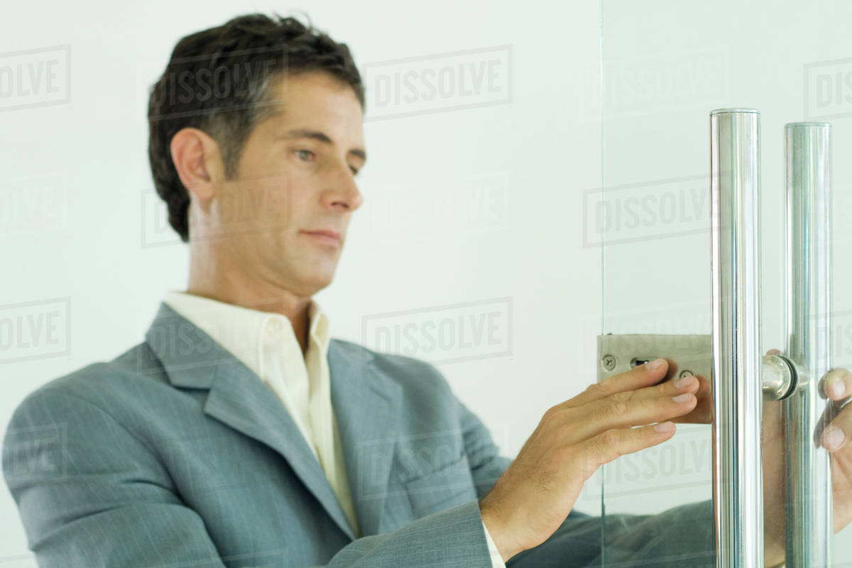 Man in suit inspecting lock on door - Royalty-free Stock Photo | Dissolve