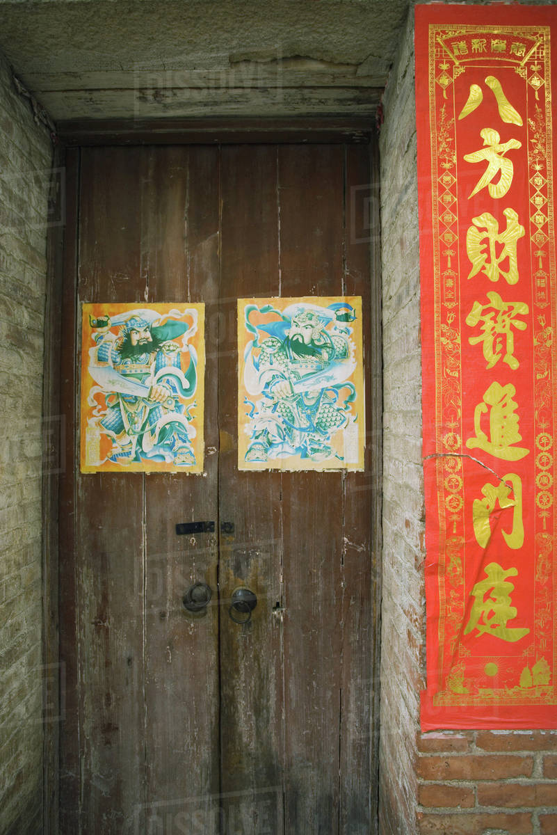 China, doorway with posters, banner with Chinese script next to door ...