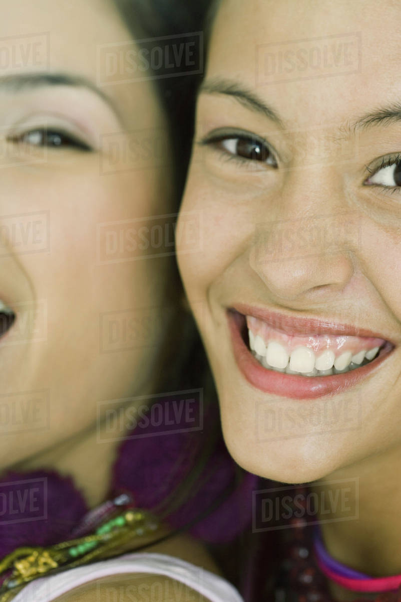 Two young friends smiling at camera together, cheek to cheek, cropped ...