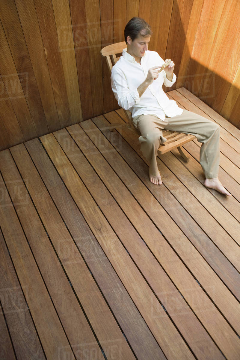 Man sitting in lounge chair looking at starfish, high angle view ...