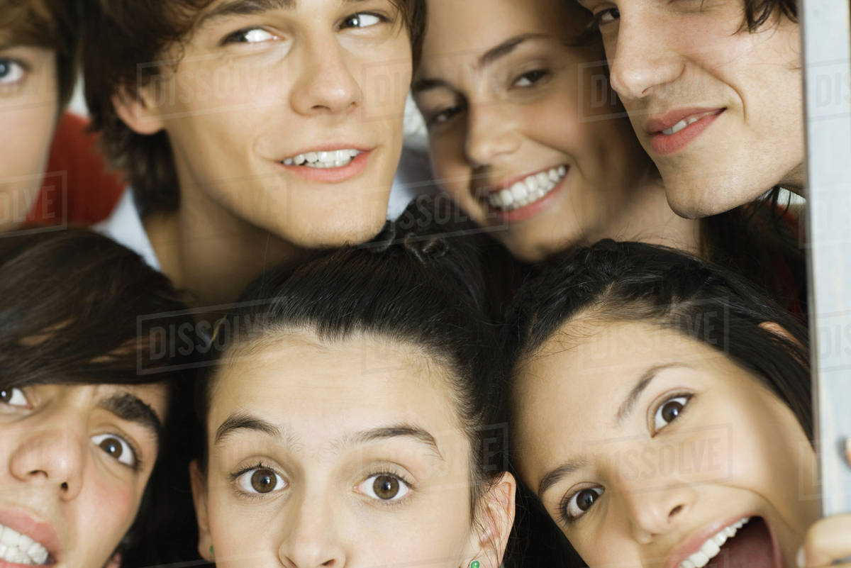 Young friends lined up and smiling together, cropped view of heads ...