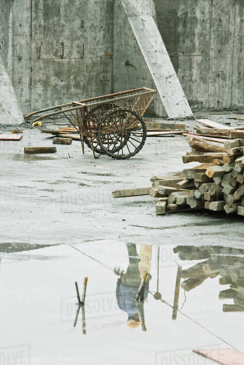 Construction worker at construction site, reflected in puddle of water ...