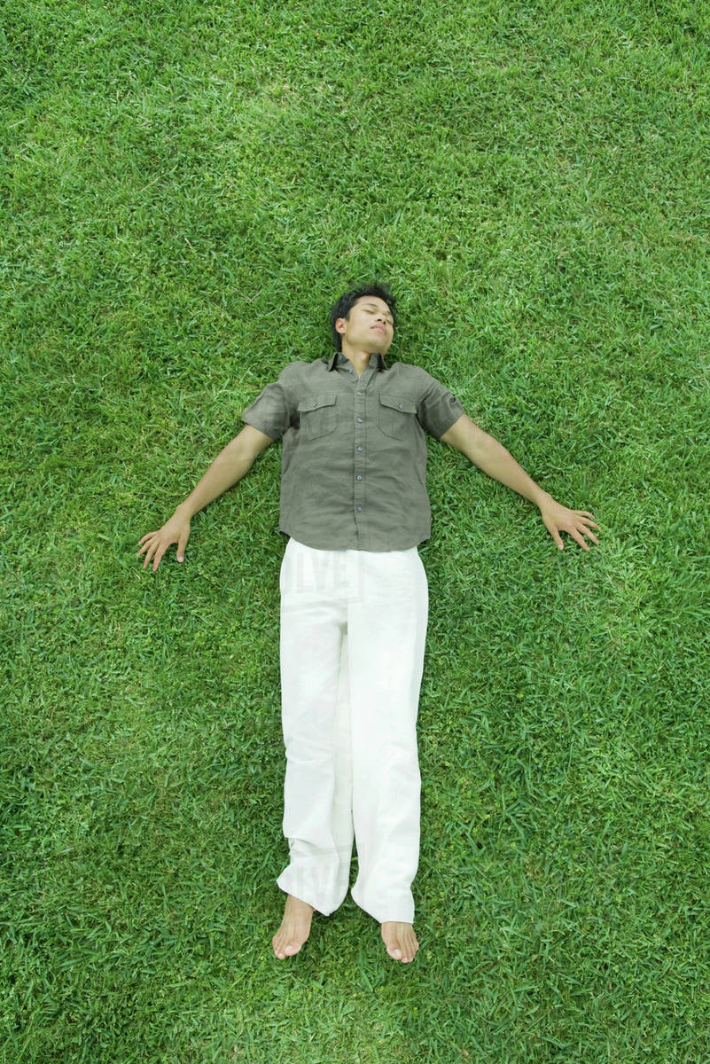 Man lying on back in grass, eyes closed, full length - Royalty-free ...
