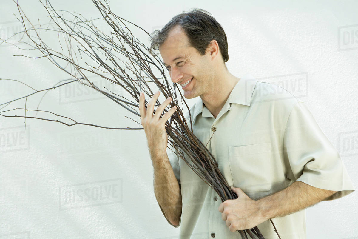 Man holding armful of twigs, smiling, looking away - Royalty-free Stock ...