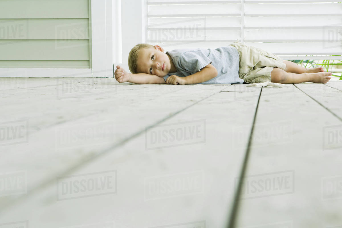 Boy lying on the ground next to starfish, head resting on arm - Royalty ...