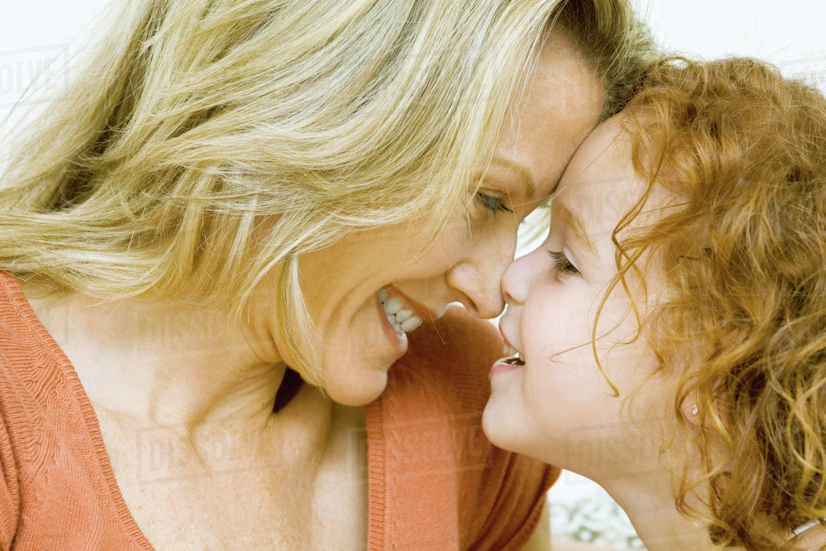 Mother and daughter touching noses and smiling at each other, cropped ...