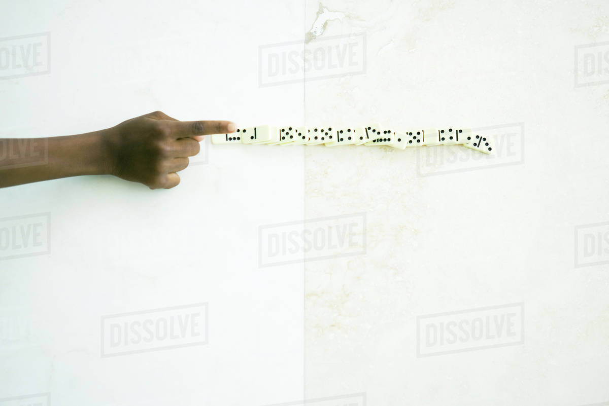 Child knocking over line of dominoes, cropped view of hand - Royalty ...