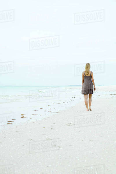 Woman in sundress walking at the beach, rear view - Royalty-free Stock ...