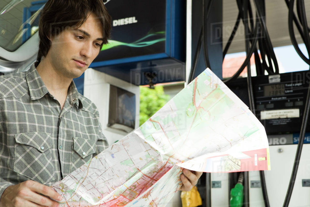 Man checking map at gas station - Royalty-free Stock Photo | Dissolve