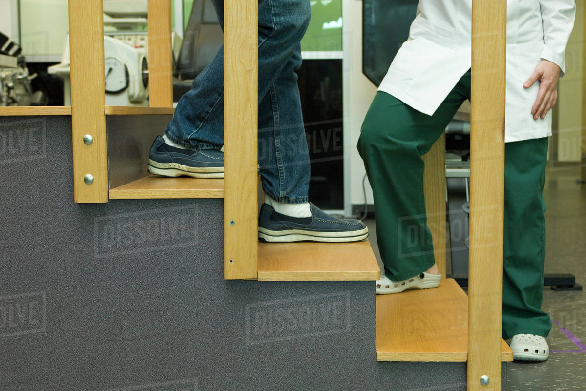 Patient practicing going down steps as part of rehabilitation exercise ...