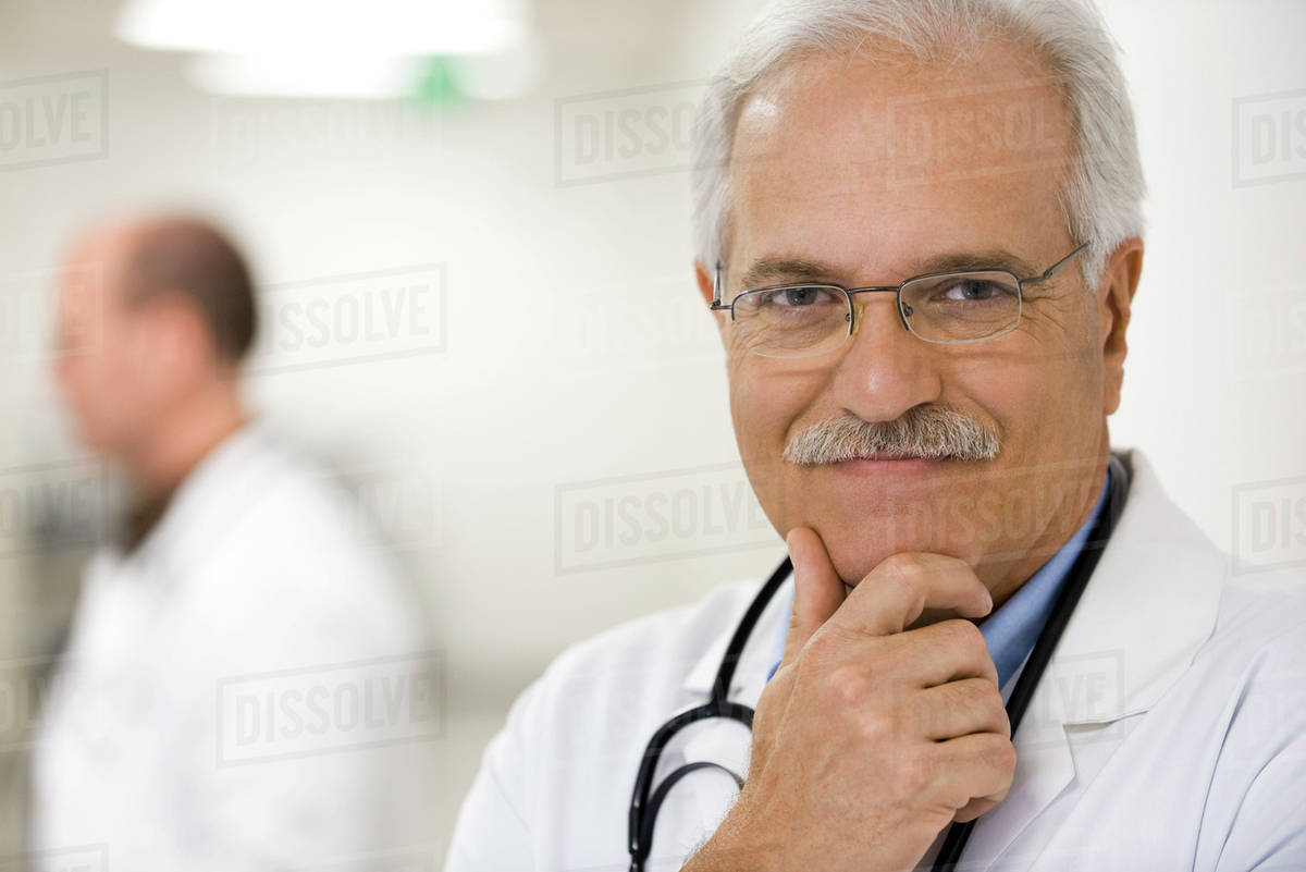 Doctor with hand under chin, portrait - Royalty-free Stock Photo | Dissolve
