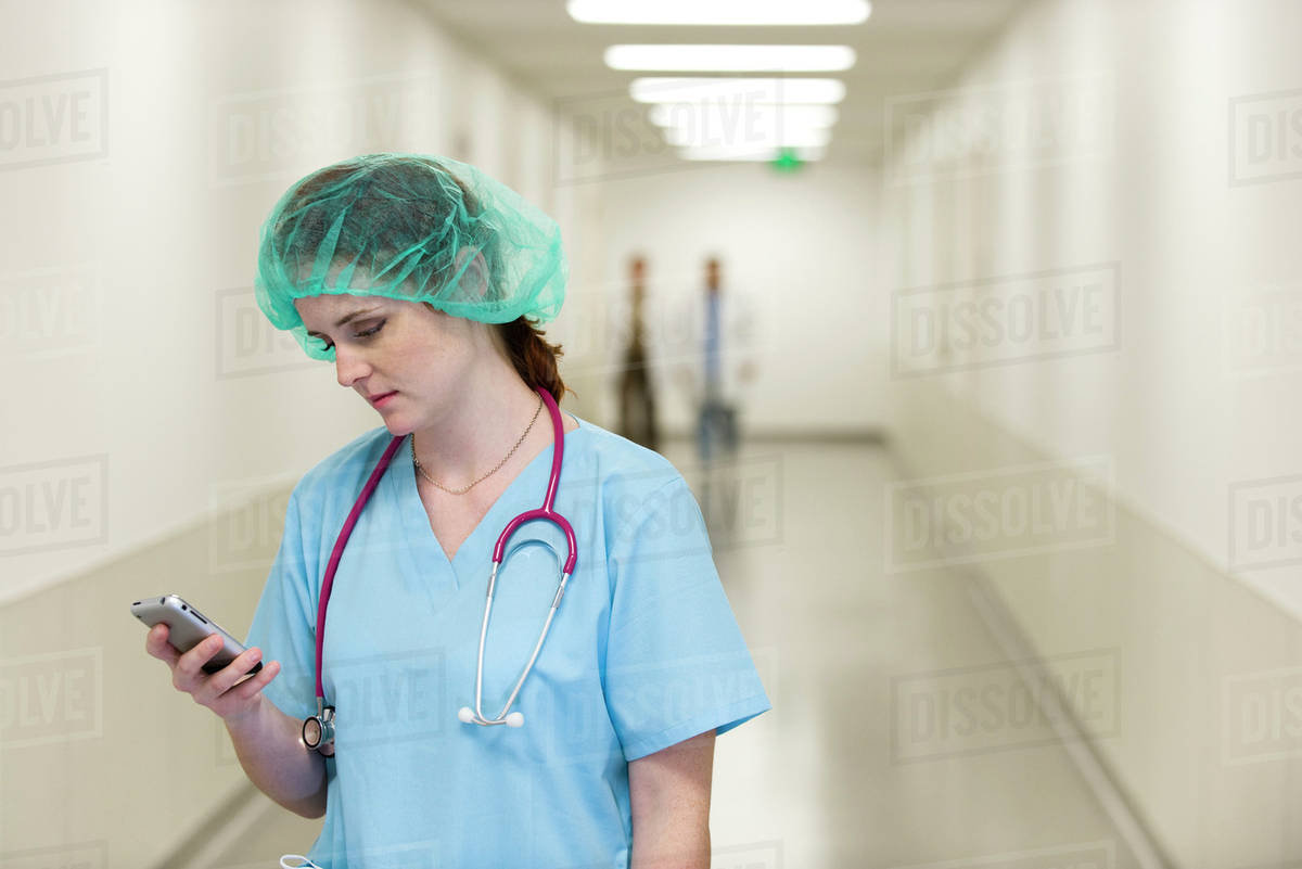 Nurse in hospital corridor using cell phone - Royalty-free Stock Photo ...