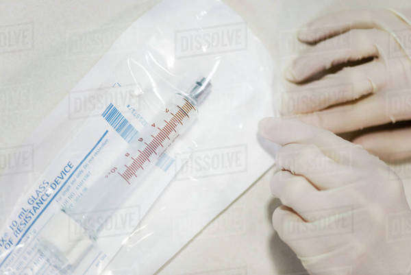 Healthcare worker opening sterile package containing medical syringe ...