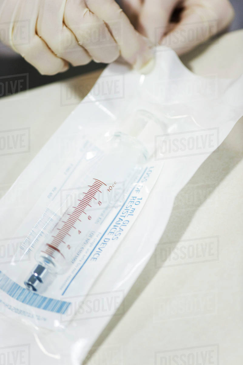 Healthcare worker opening sterile package containing medical syringe ...