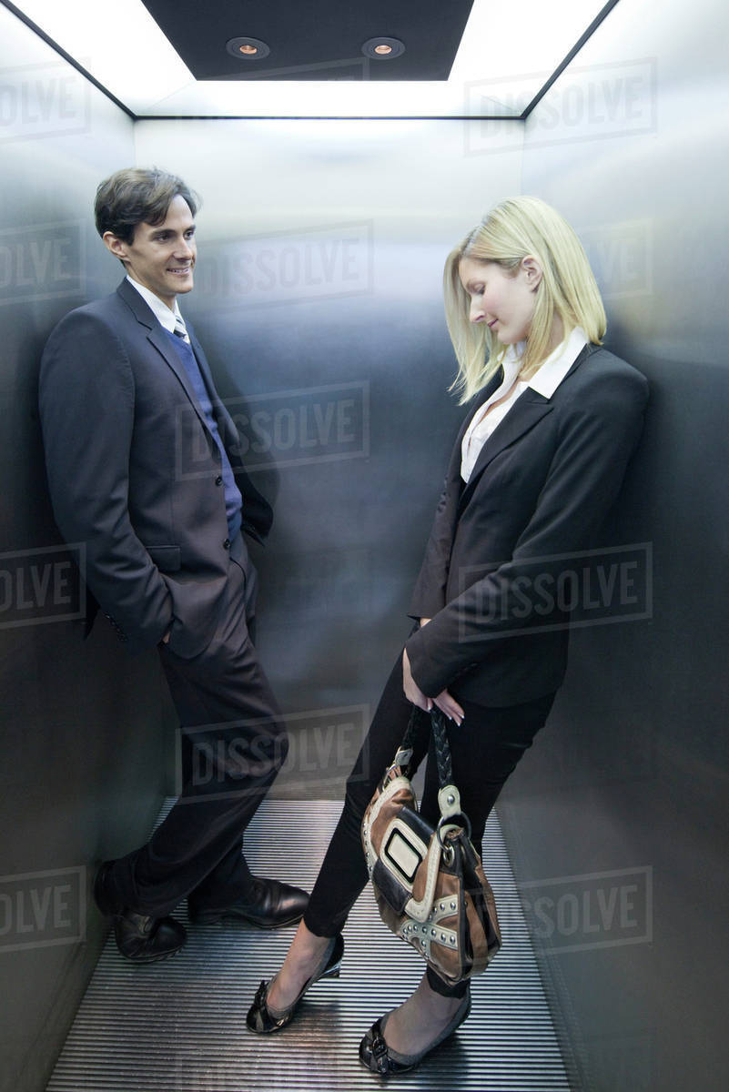 Colleagues flirting in elevator - Stock Photo - Dissolve