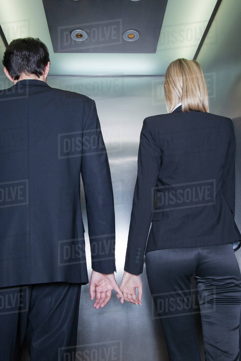 Professionals holding hands in elevator, rear view - Royalty-free Stock ...