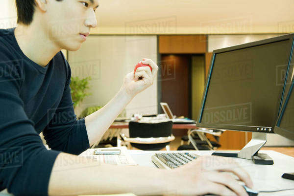 Office worker using computer, squeezing stress ball with one hand ...
