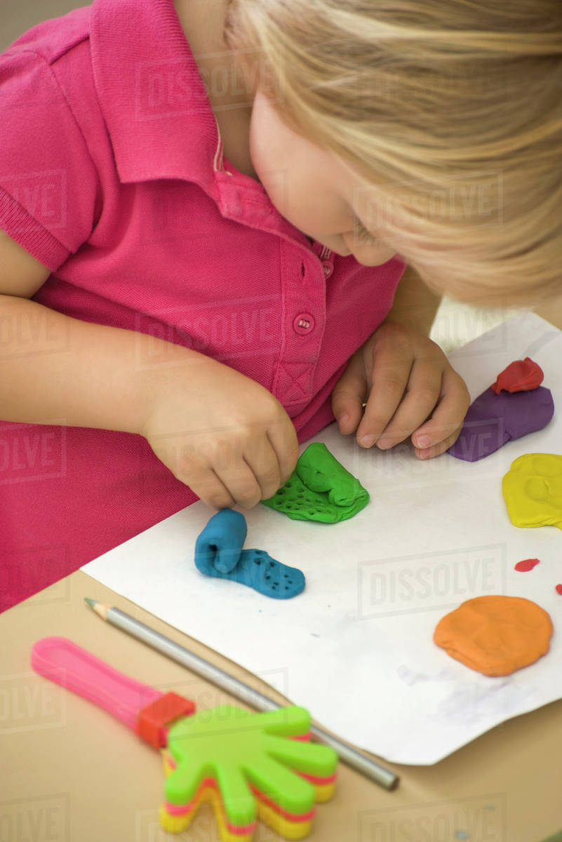 Little girl playing with clay - Royalty-free Stock Photo | Dissolve