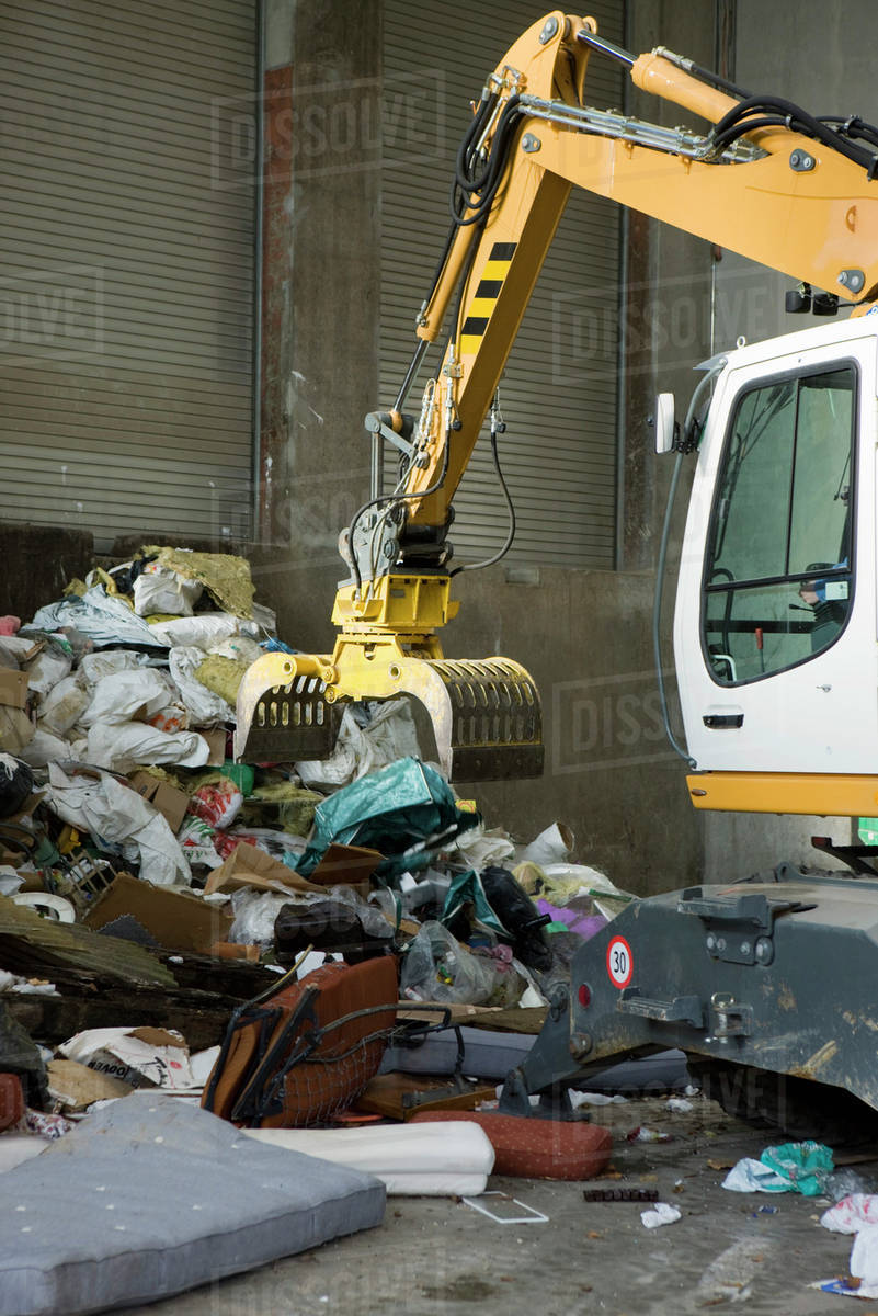 Earth mover picking up trash from large heap - Stock Photo - Dissolve
