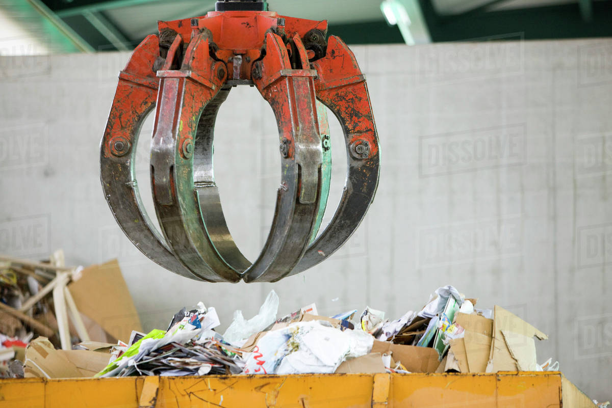 Grapple hanging over bin of waste paper in recycling center - Royalty ...