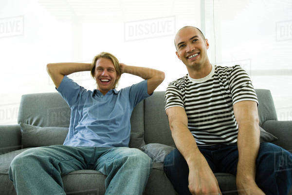 Two men sitting on sofa, laughing - Stock Photo - Dissolve