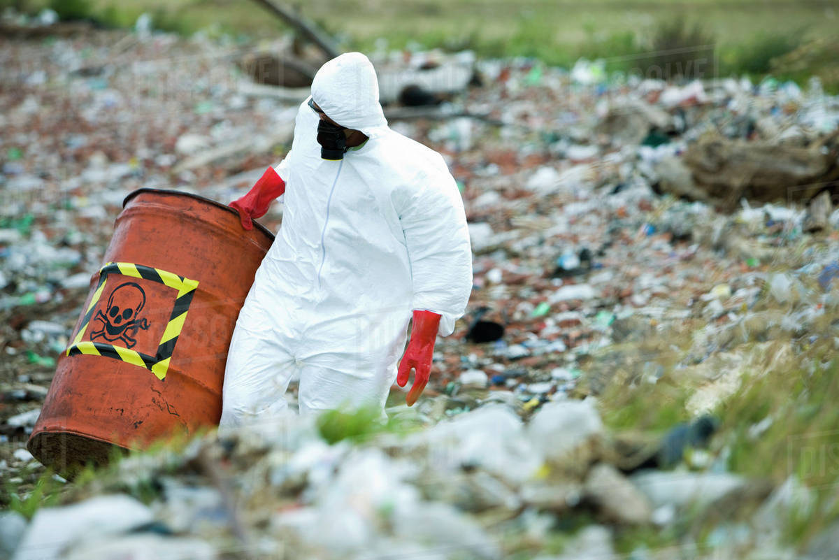 Person in protective suit carrying barrel of hazardous waste - Stock ...