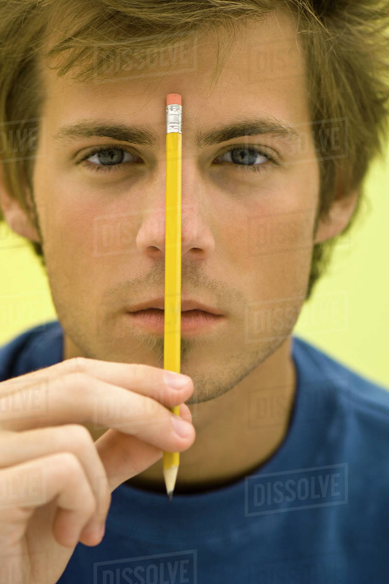 Young man holding up pencil - Royalty-free Stock Photo | Dissolve