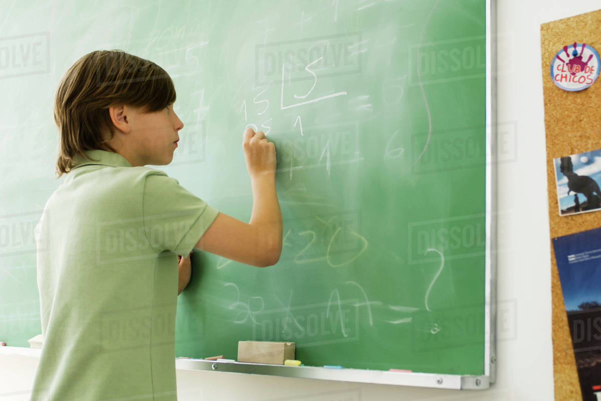 Boy writing with chalk on blackboard - Royalty-free Stock Photo | Dissolve