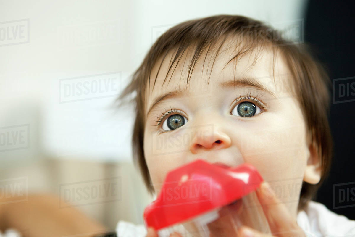 Baby girl chewing on plastic cup - Stock Photo - Dissolve