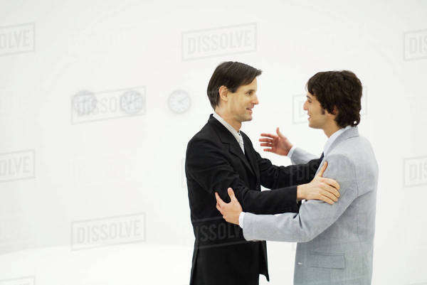 Two male business partners standing face to face, hands on each other's ...