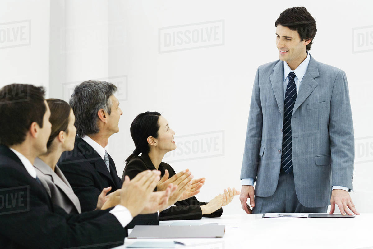 Group of business associates applauding colleague during meeting ...