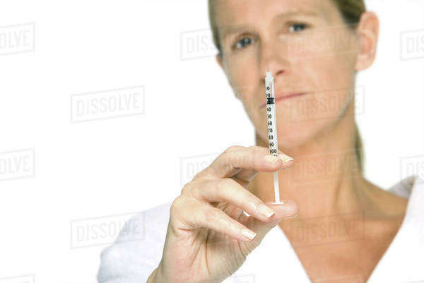 Woman holding up syringe, looking at camera - Royalty-free Stock Photo ...