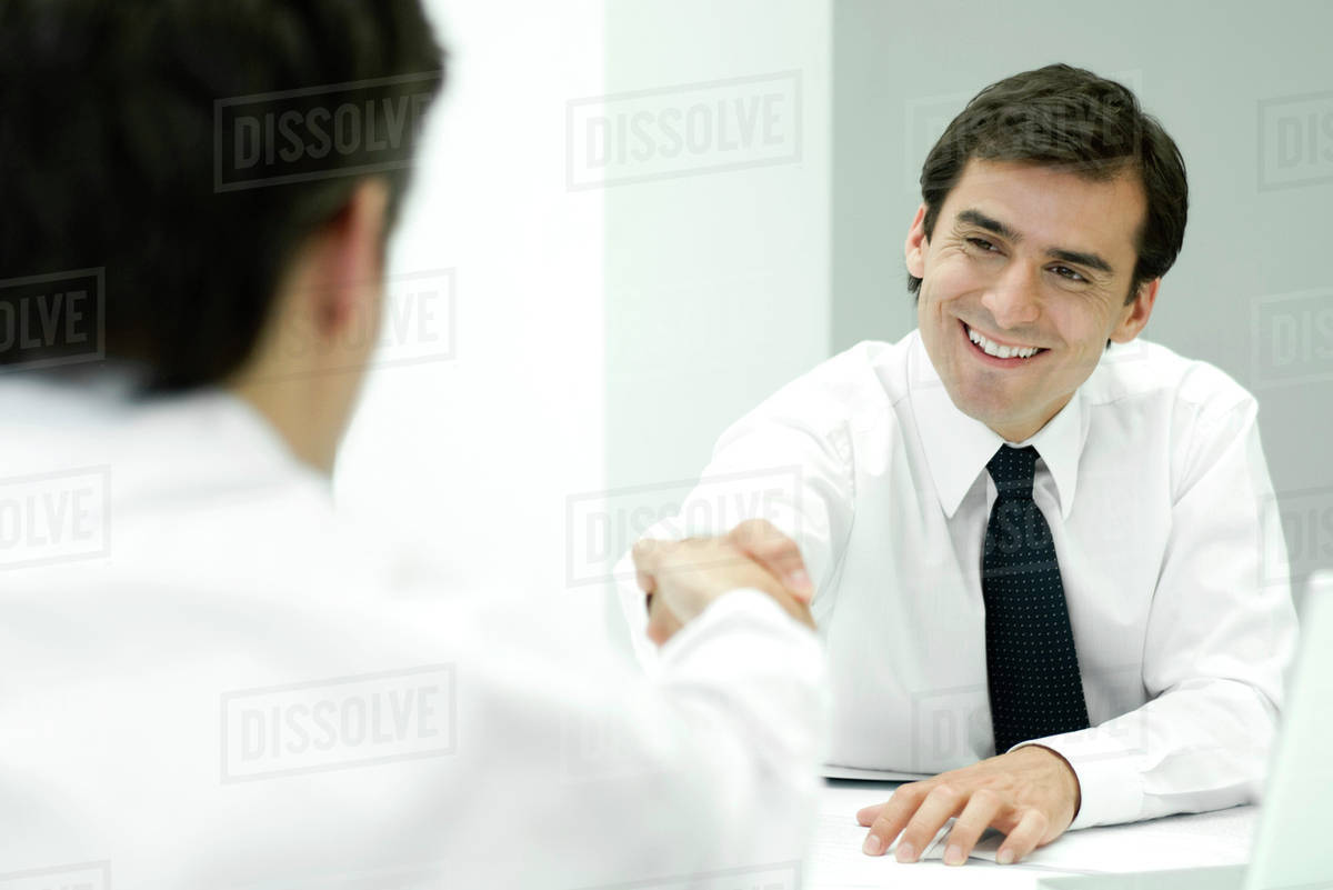 Two businessmen shaking hands, over the shoulder view - Royalty-free ...