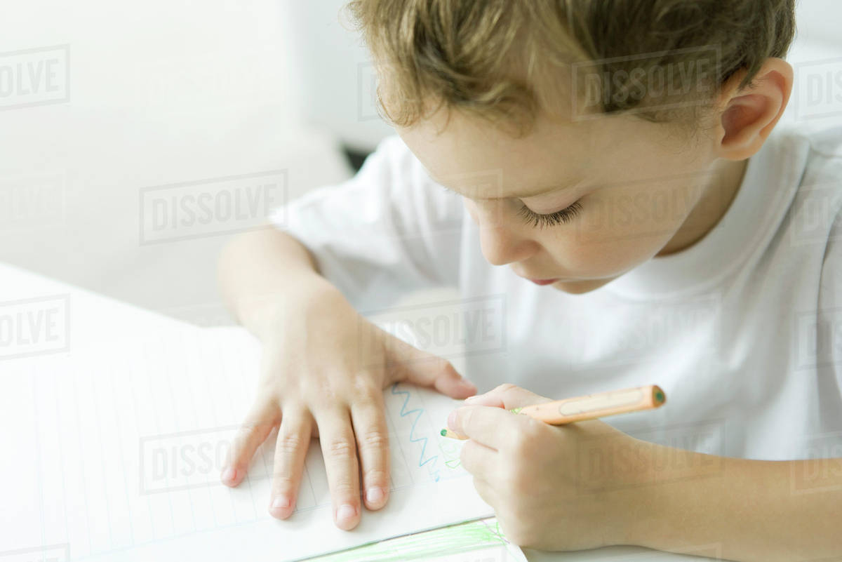 Little boy sitting at table, drawing with colored pencil - Royalty-free ...