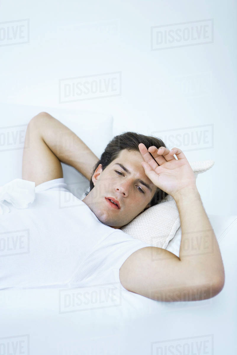 Man lying on sofa with tissue on his chest, hand on forehead - Royalty ...