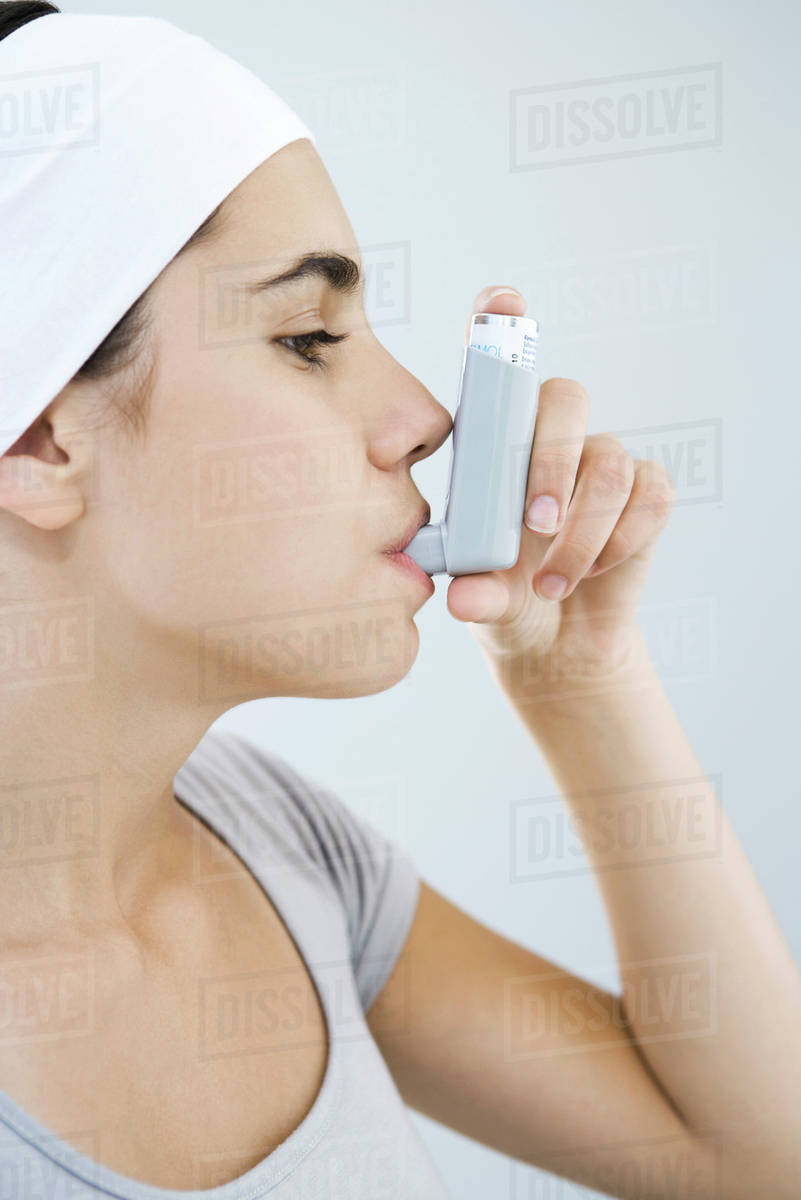 Teen girl using inhaler, side view - Royalty-free Stock Photo | Dissolve