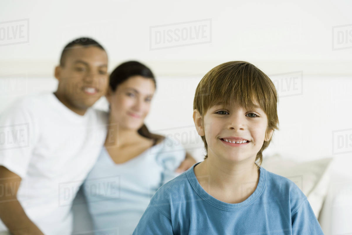 Boy smiling at camera, parents sitting in background - Stock Photo ...