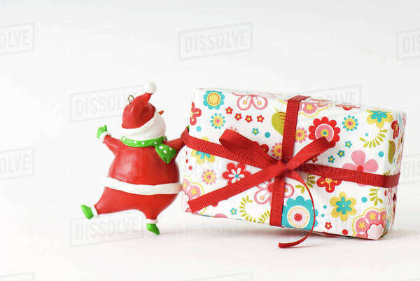 Santa Claus figurine pulling Christmas present - Stock Photo - Dissolve