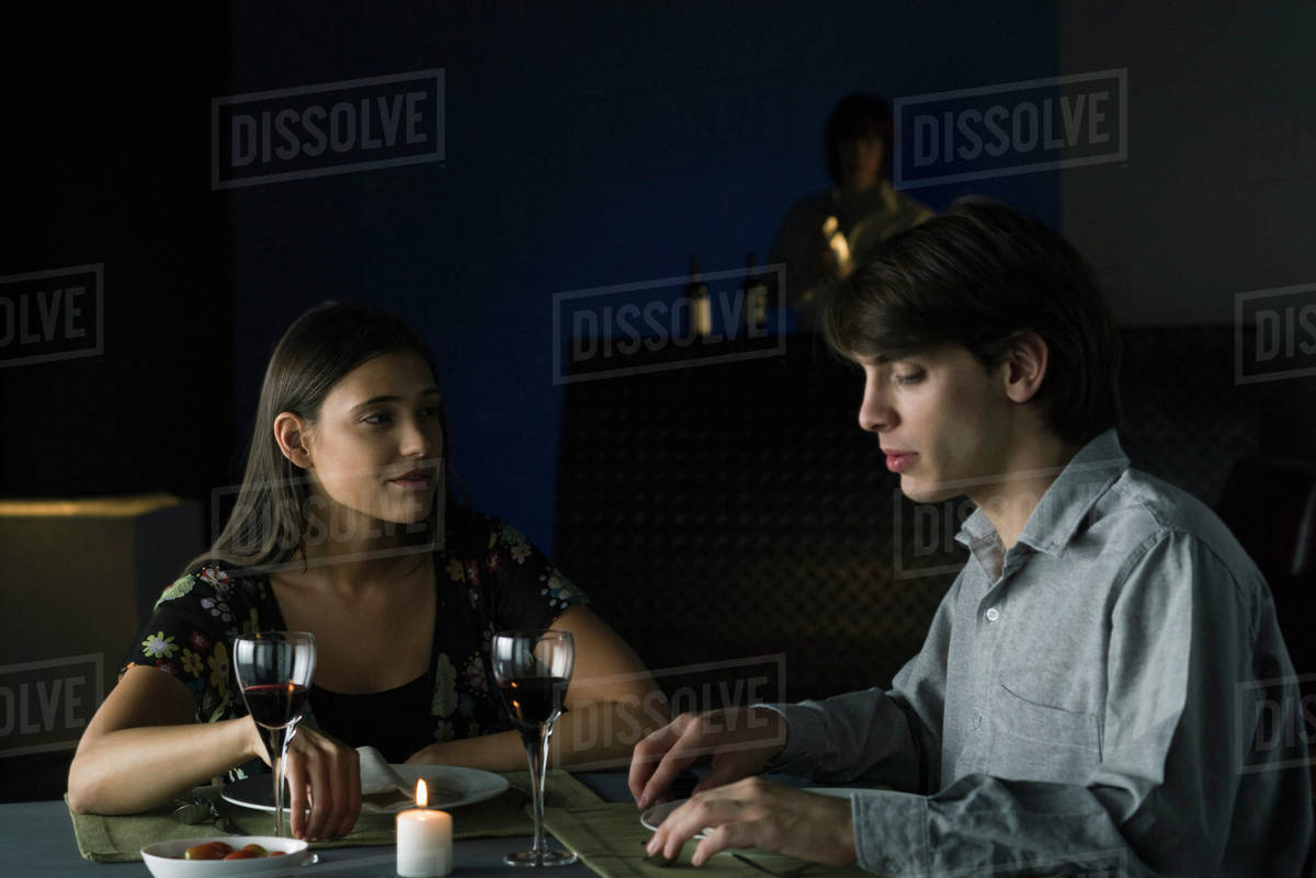 Couple having serious conversation over dinner with wine at restaurant ...