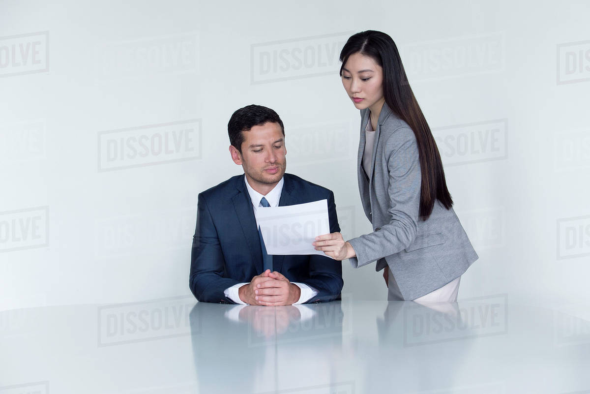 Business associates looking at document in meeting - Stock Photo - Dissolve
