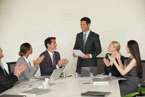 Executve being applauded by colleagues in meeting - Stock Photo - Dissolve