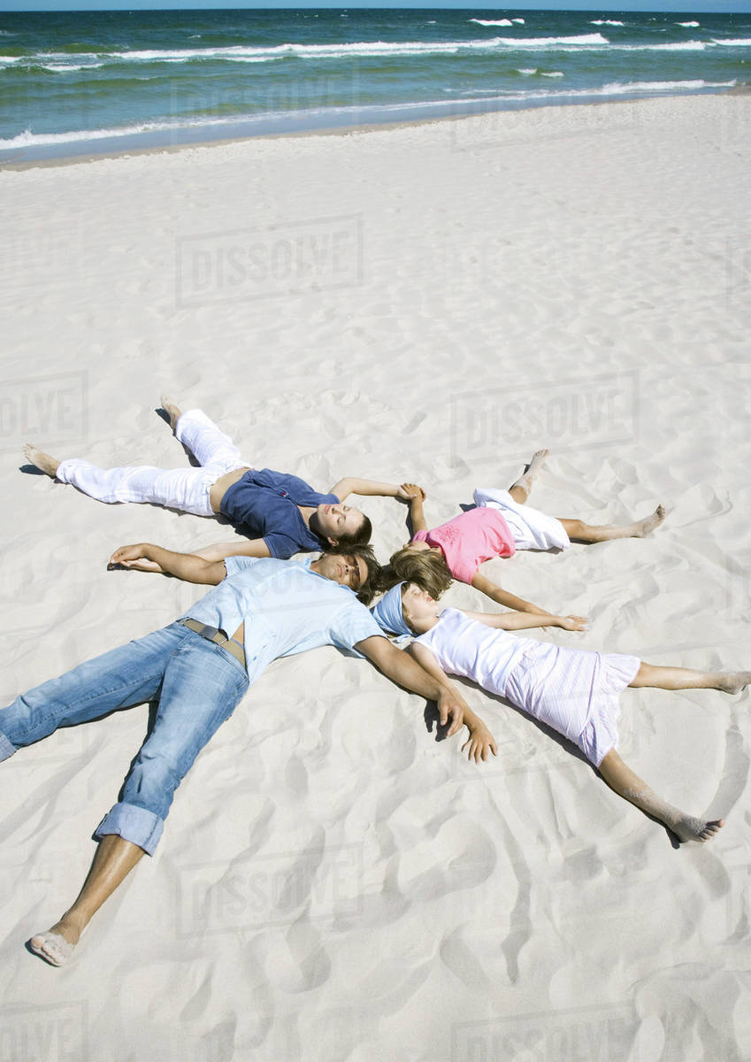 Family lying on sand, heads together and arms and legs out - Royalty ...