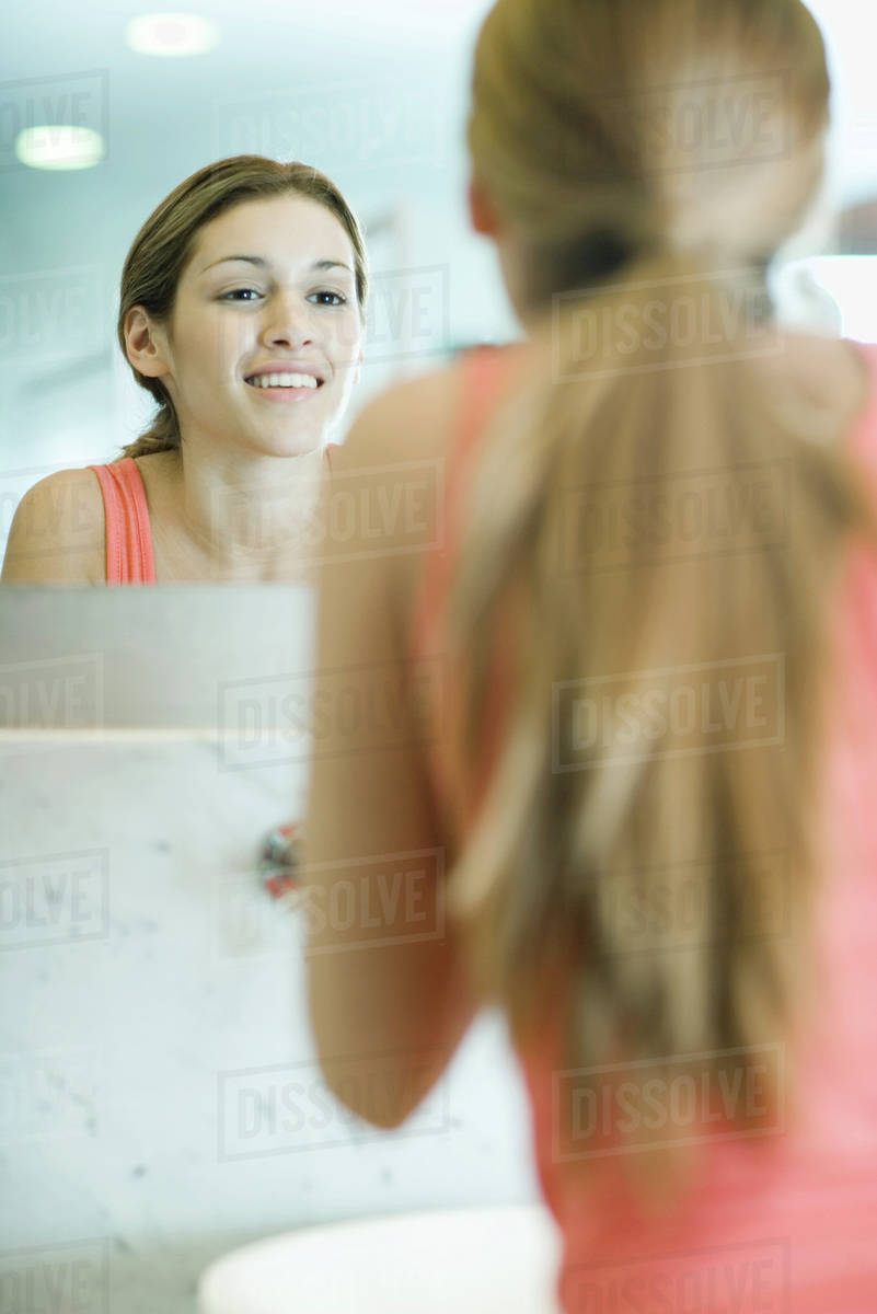 Young woman looking at self in mirror - Royalty-free Stock Photo | Dissolve