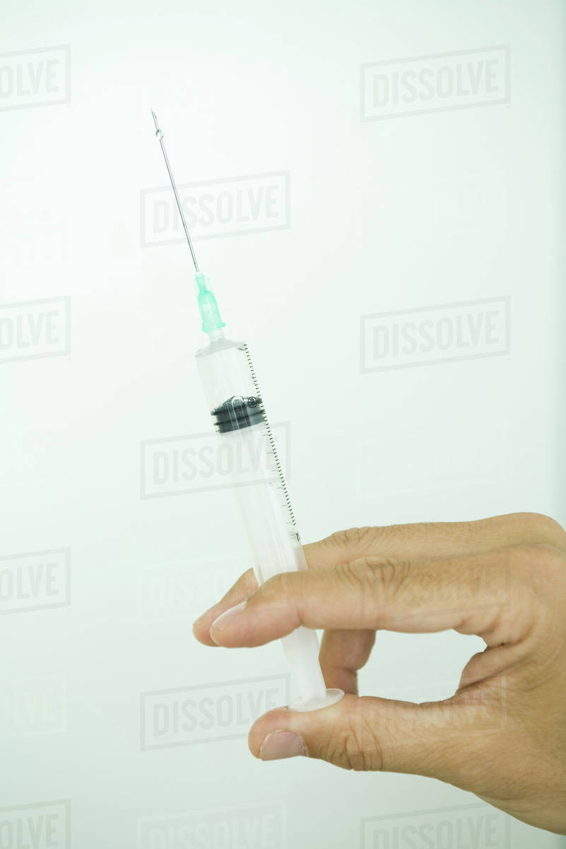 Hand holding syringe - Stock Photo - Dissolve