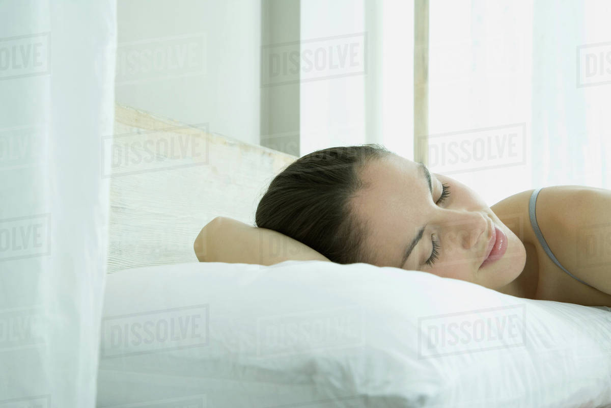 Woman lying in bed, eyes closed and smiling - Royalty-free Stock Photo | Dissolve